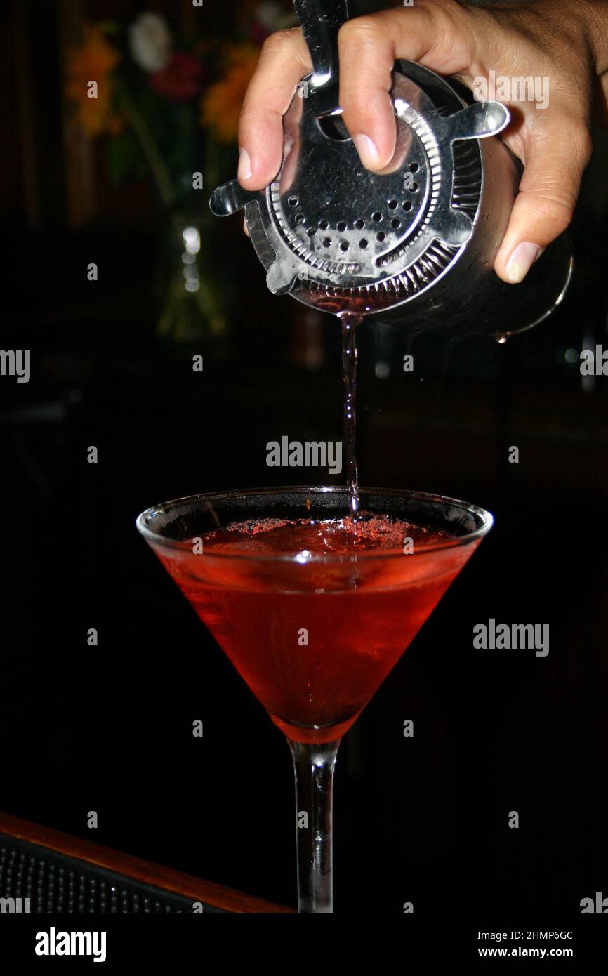 bartender pouring a cosmopolitan into a martini glass at the bar Stock ...