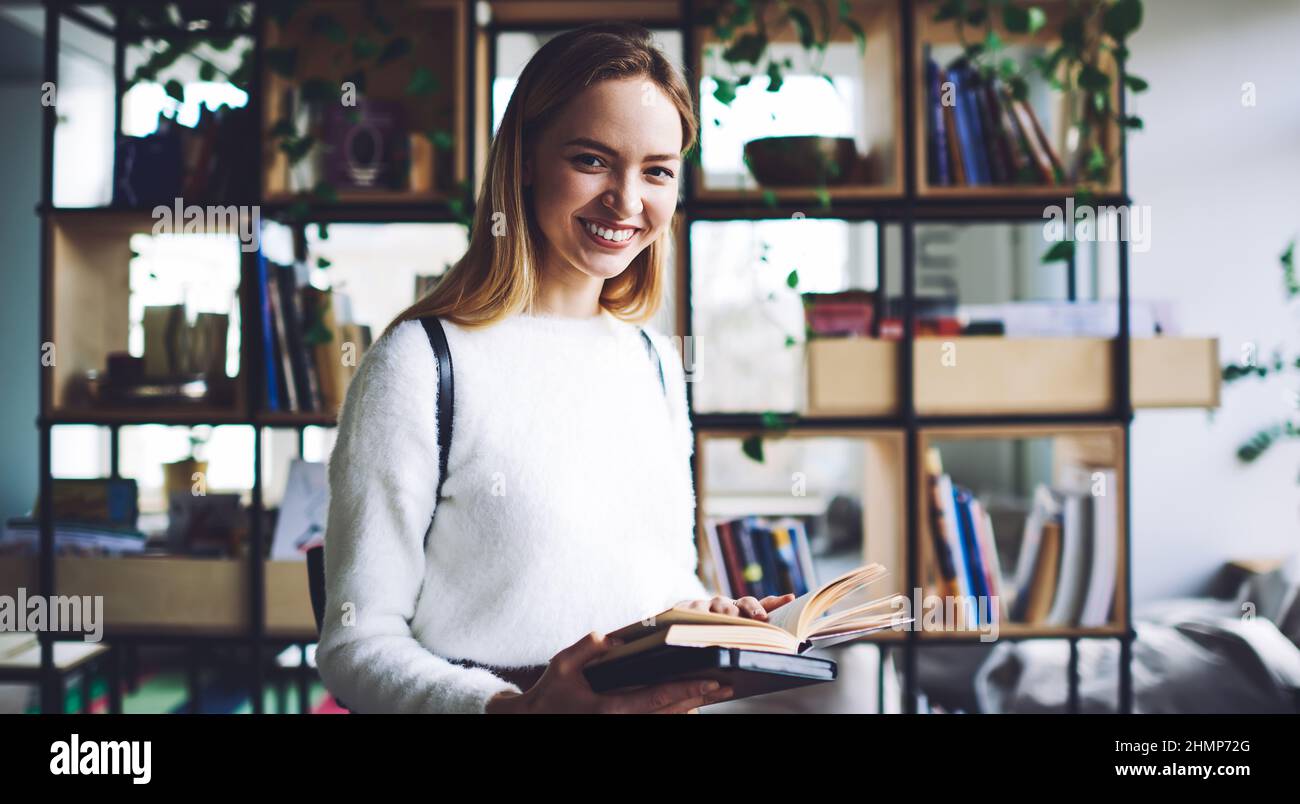 Happy teenager reading book in library Stock Photo - Alamy