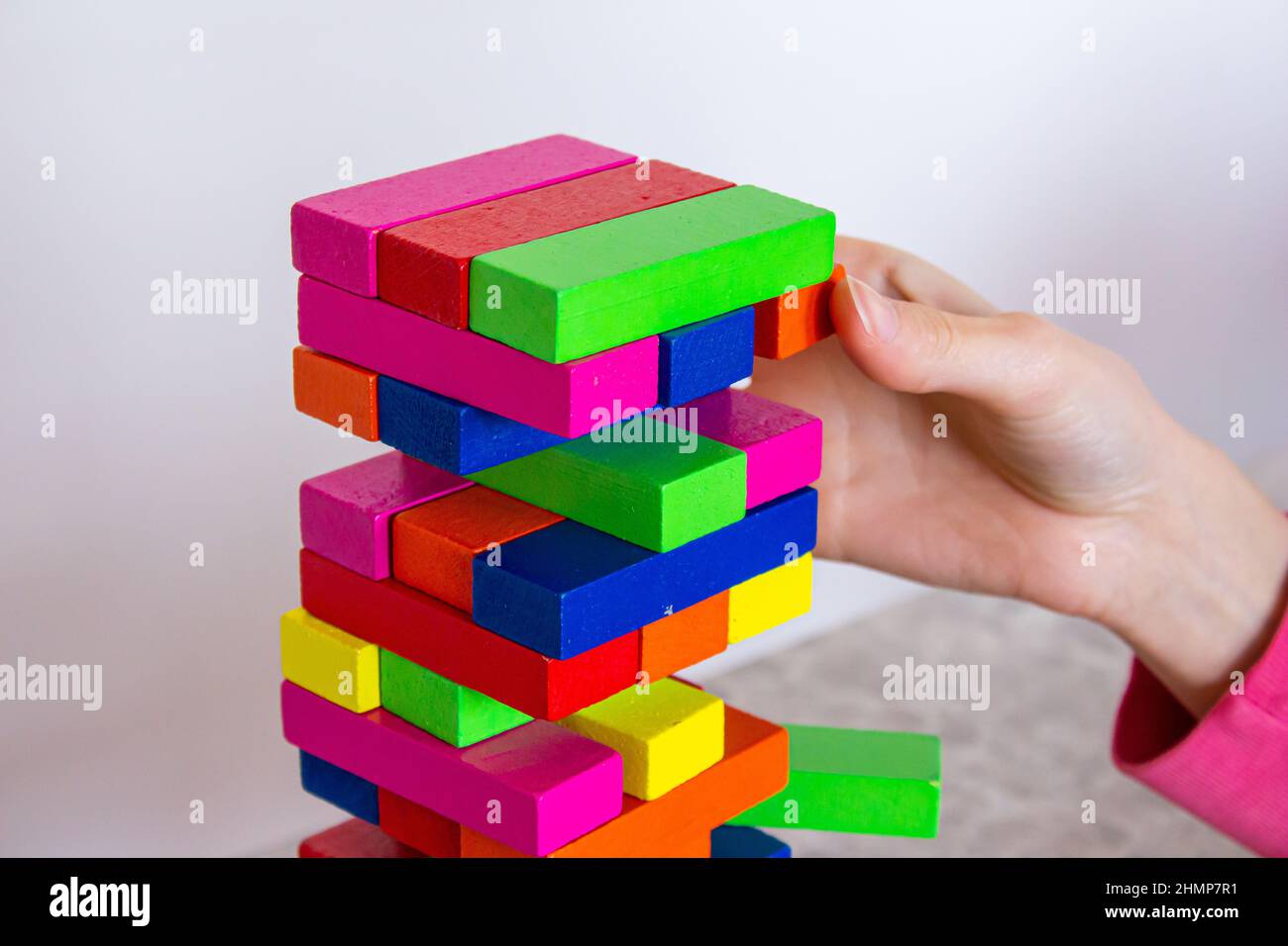Playing wooden tower game in home. Hand holding colorful wooden blocks ...