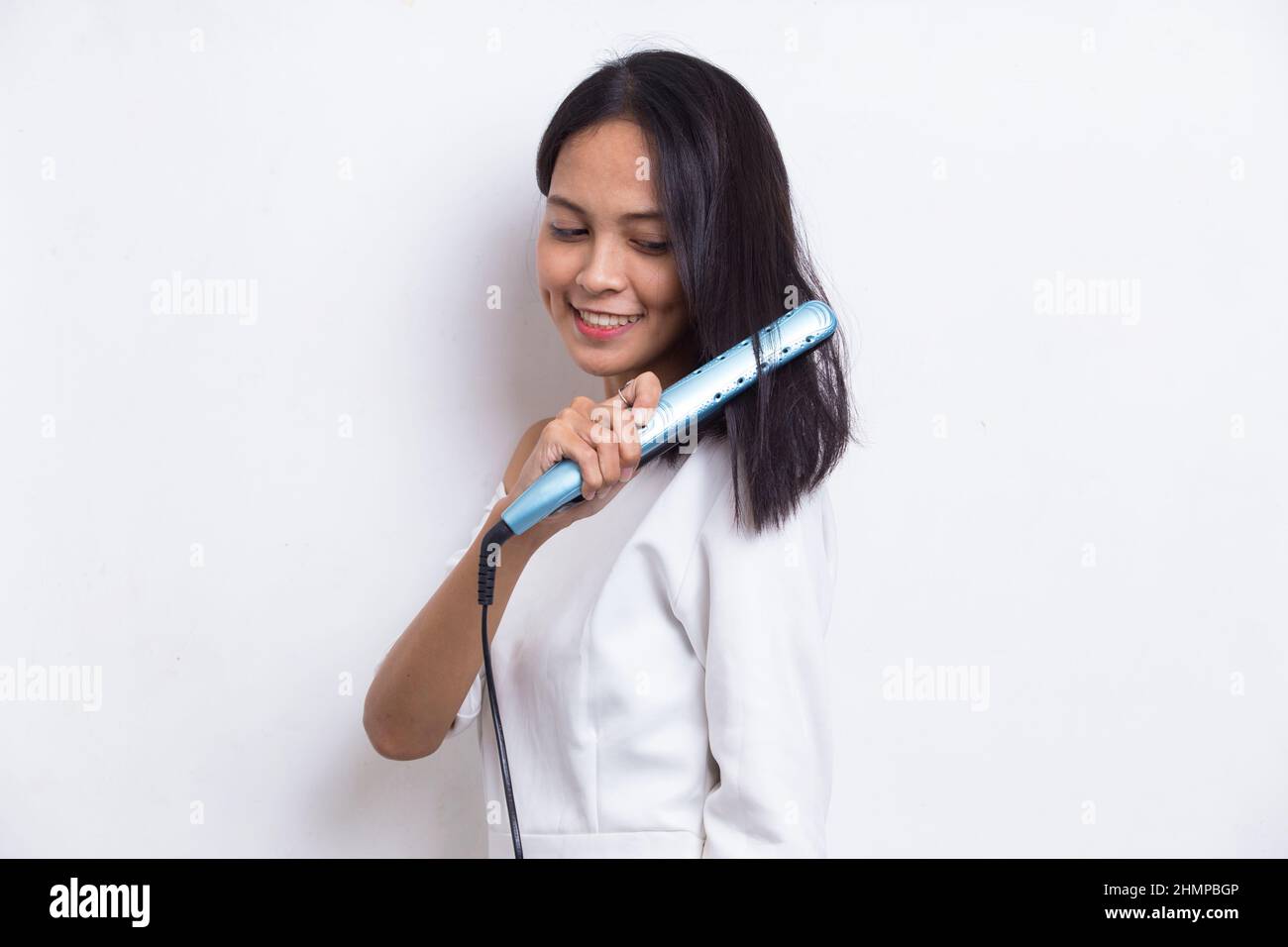 young asian beautiful happy woman straightening hair with hair ...