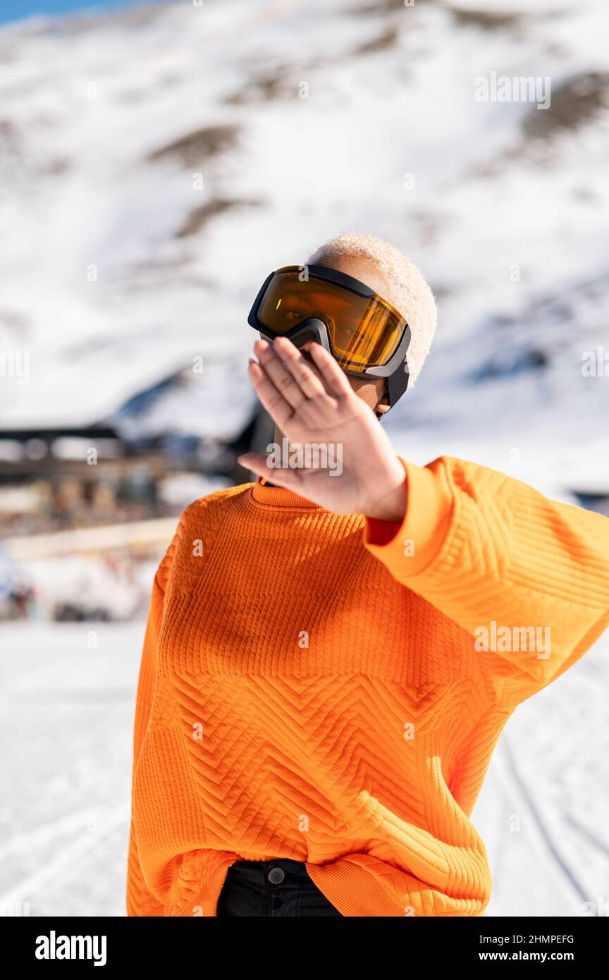 African American woman wearing goggles standing in snowy mountain ...