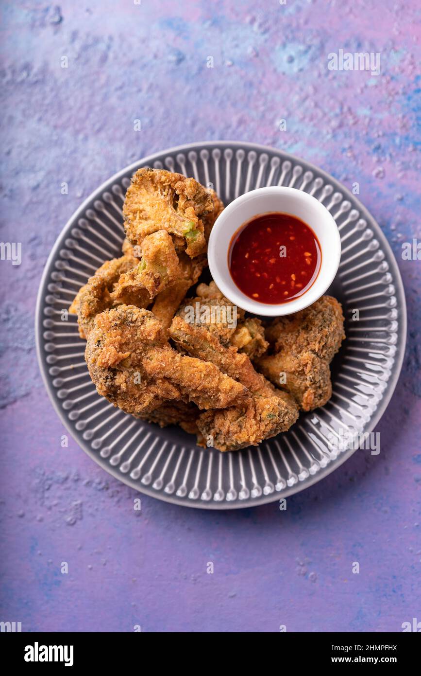 Asian fusion vegan meat-free meal of battered fried broccoli with sweet ...