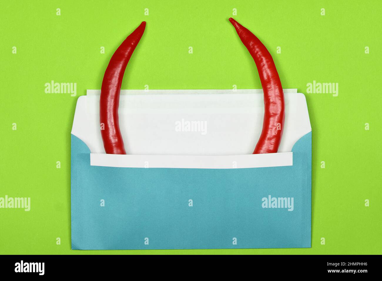 Red chili pepper in a mailing envelope isolated on a green background ...