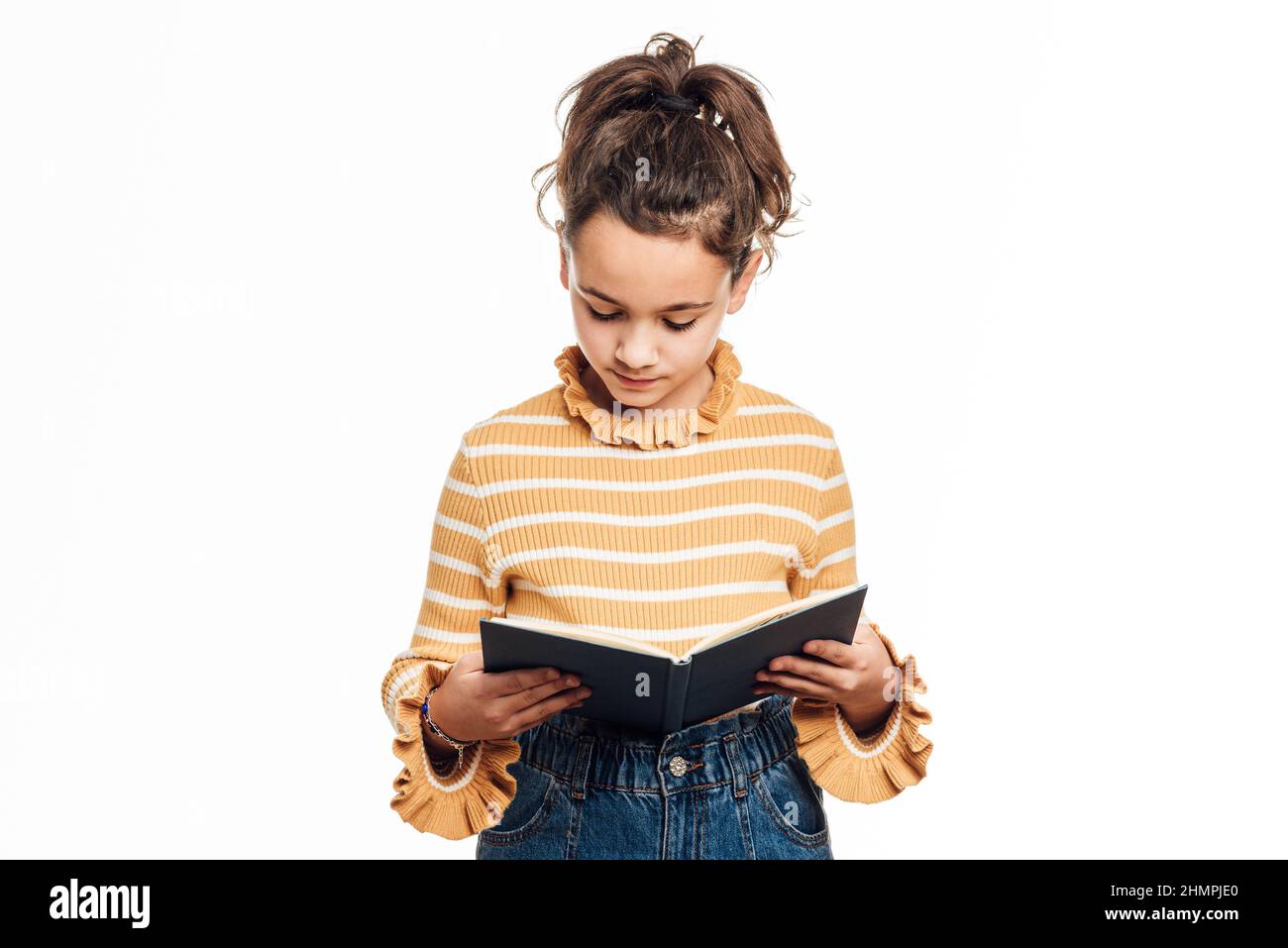 Young girl reading a book while standing on an isolated white ...
