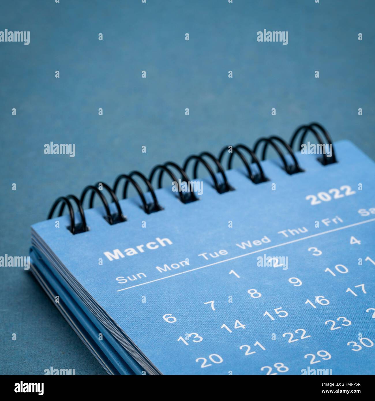 March 2022 - spiral desktop calendar against textured paper, time and ...