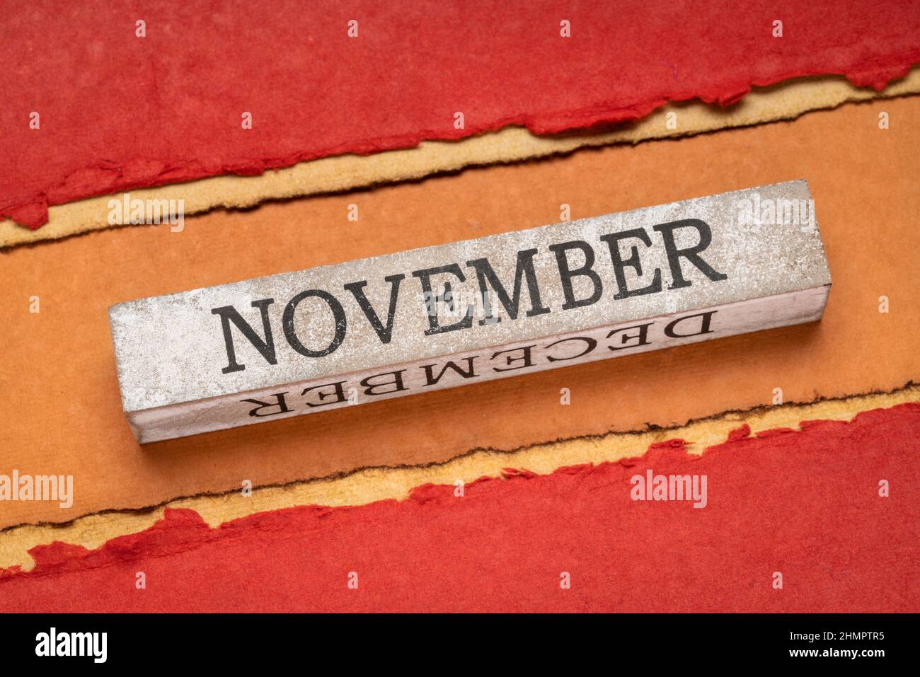 November text on grunge wooden block against handmade rag paper in red ...