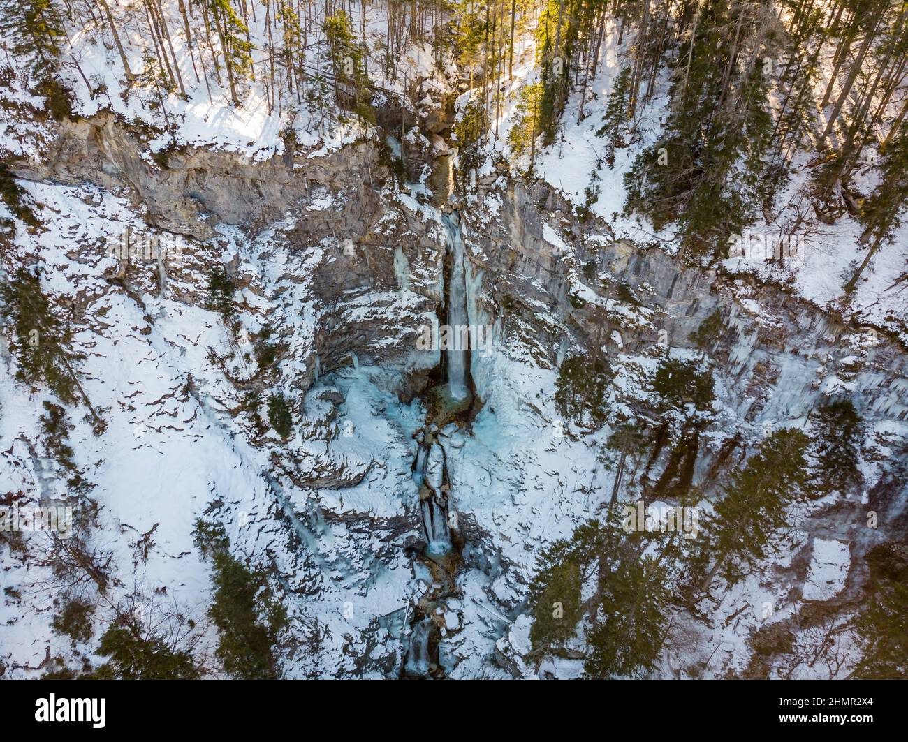 Spectacular drop down view of waterfall falling over rocky forest ledge ...