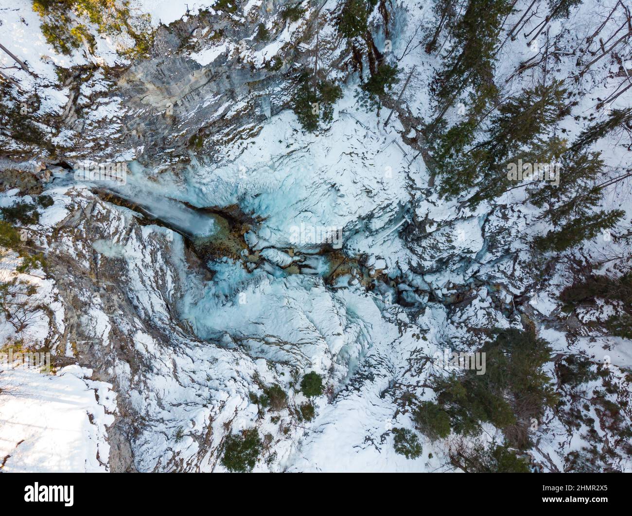 Spectacular drop down view of waterfall falling over rocky forest ledge ...
