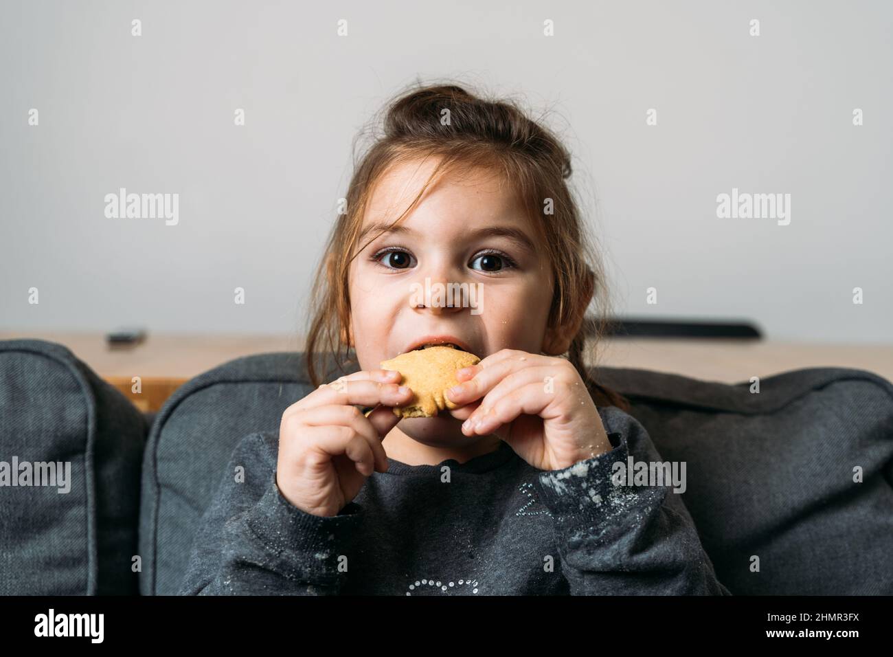 Pretty caucasian girl eating cookies at home on the sofa Stock Photo ...