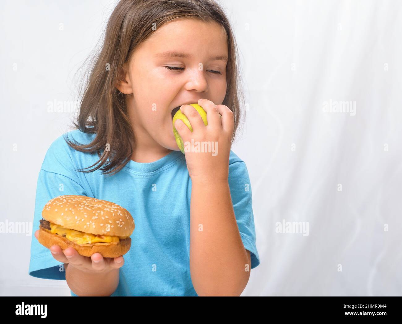 Child girl biting an apple instead of a hamburger. Healthy food Stock ...