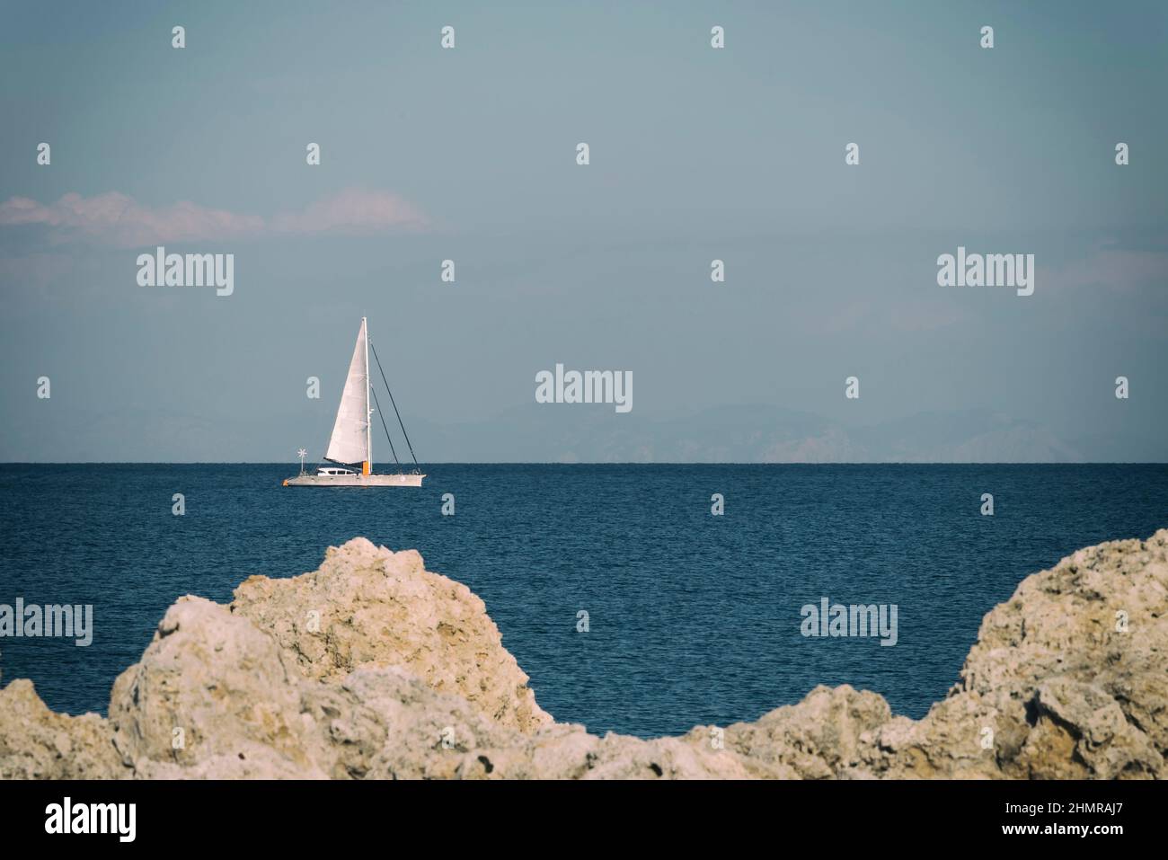 Sailboat on the sea with rock formation in the foreground Stock Photo ...