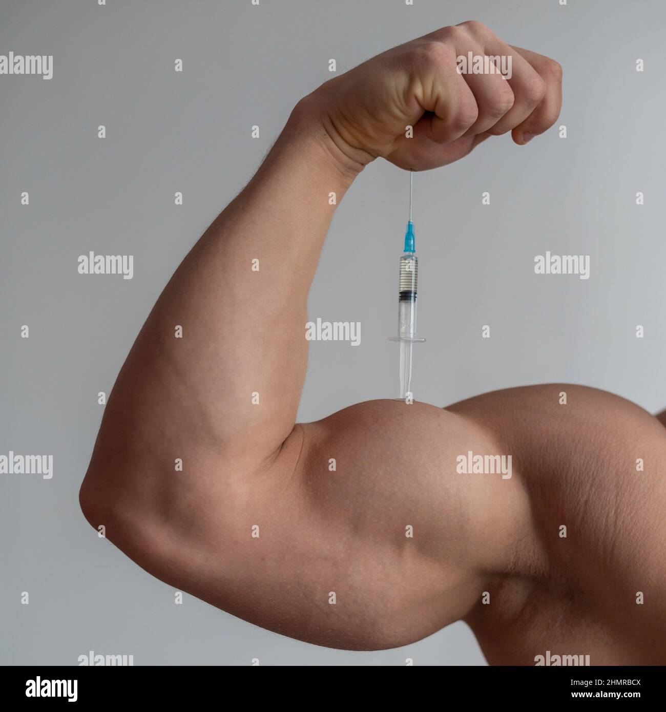 Closeup of a male hand with a dope syringe. Cropped biceps of a man ...