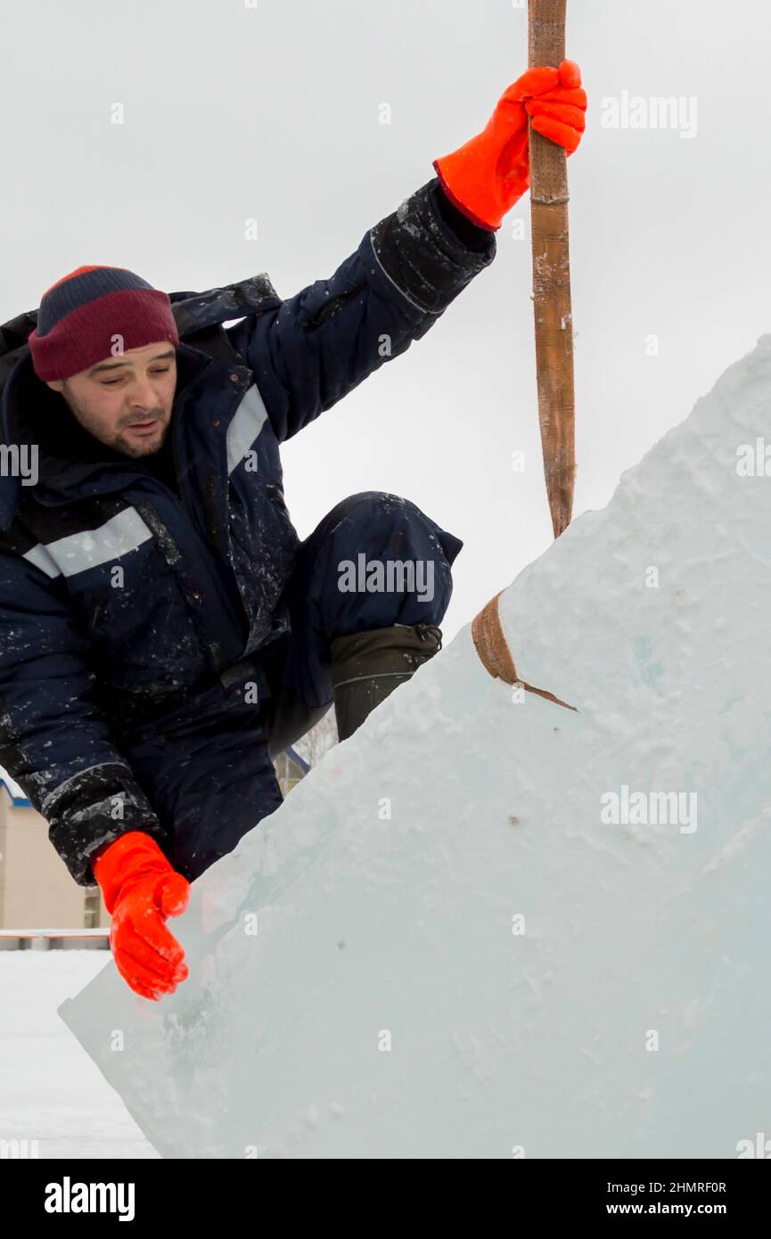 The installer stands on the ice block holding on to the tape sling ...