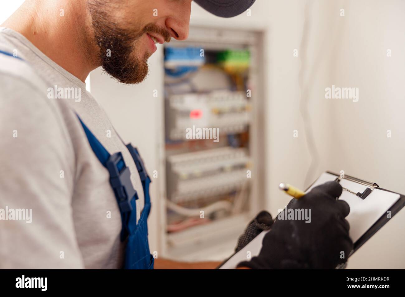 Closeup of electrician writing on a clipboard the data collected on a ...