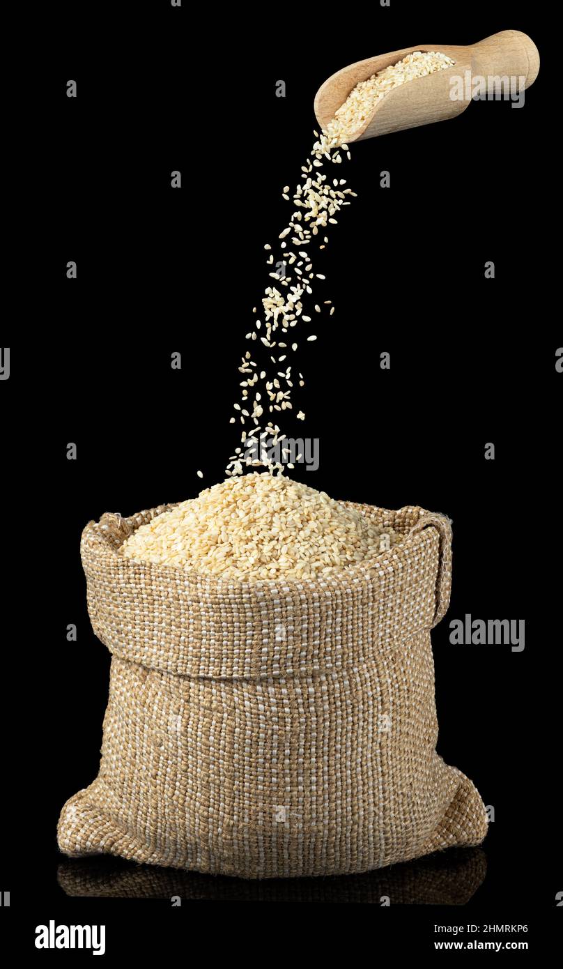 sesame seeds falling from wooden scoop in burlap bag Stock Photo - Alamy
