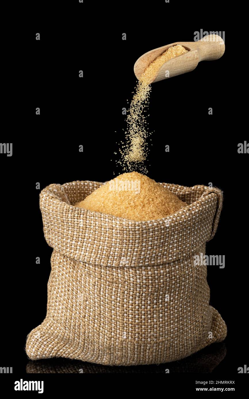 brown cane sugar falling from wooden scoop in burlap bag Stock Photo ...