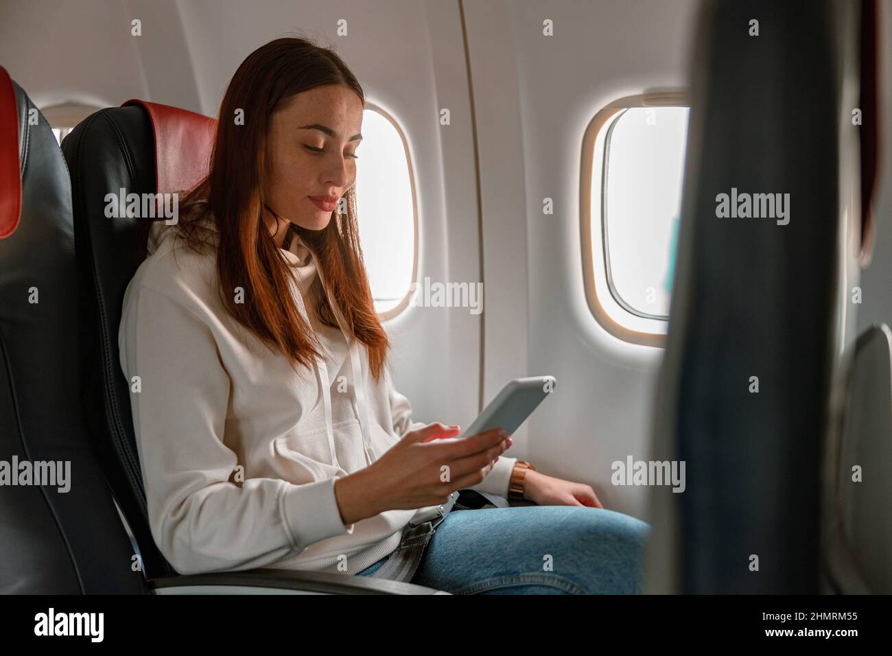Female passenger using mobile phone in airplane Stock Photo - Alamy