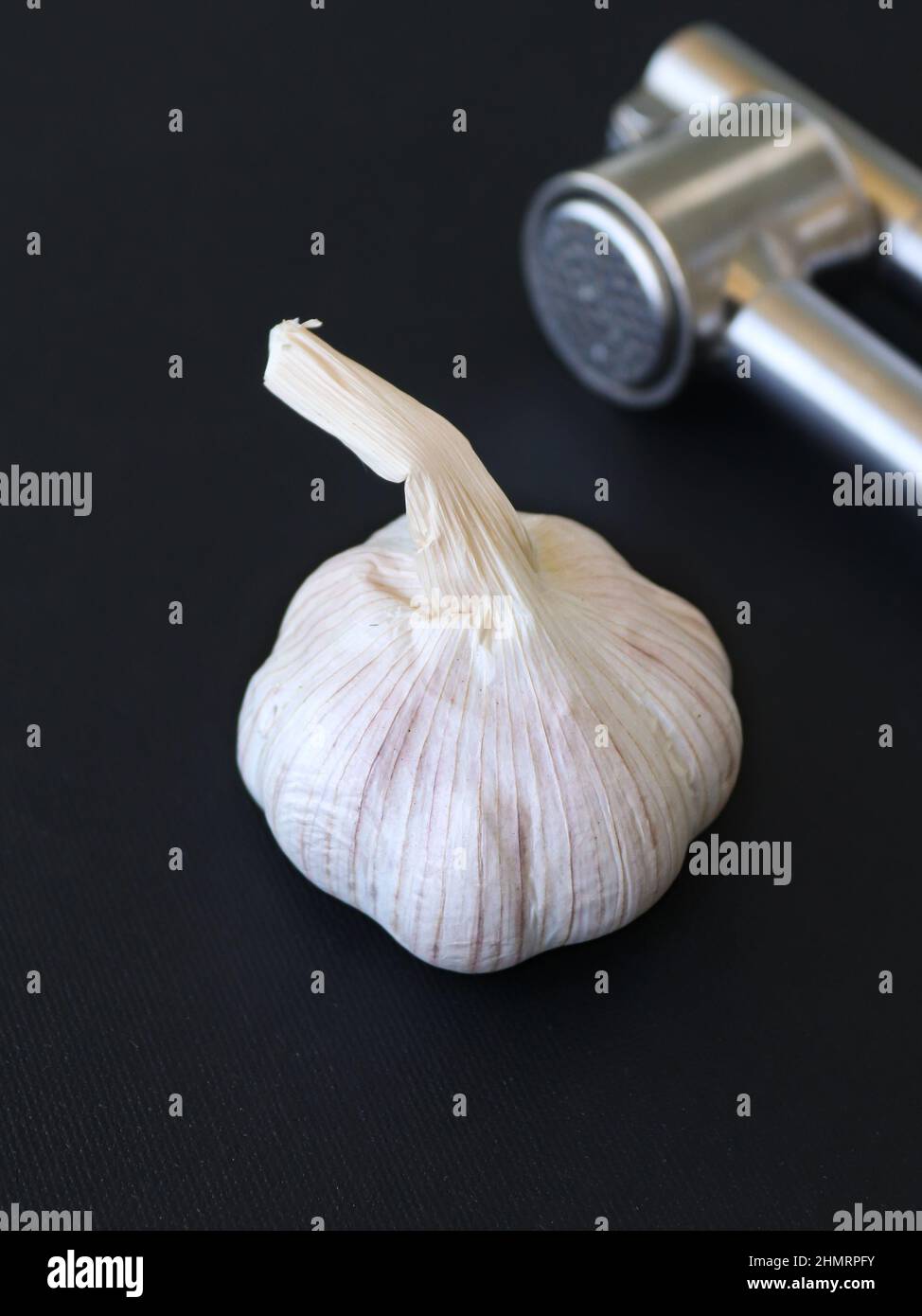 Garlic bulb and garlic press on black background Stock Photo - Alamy