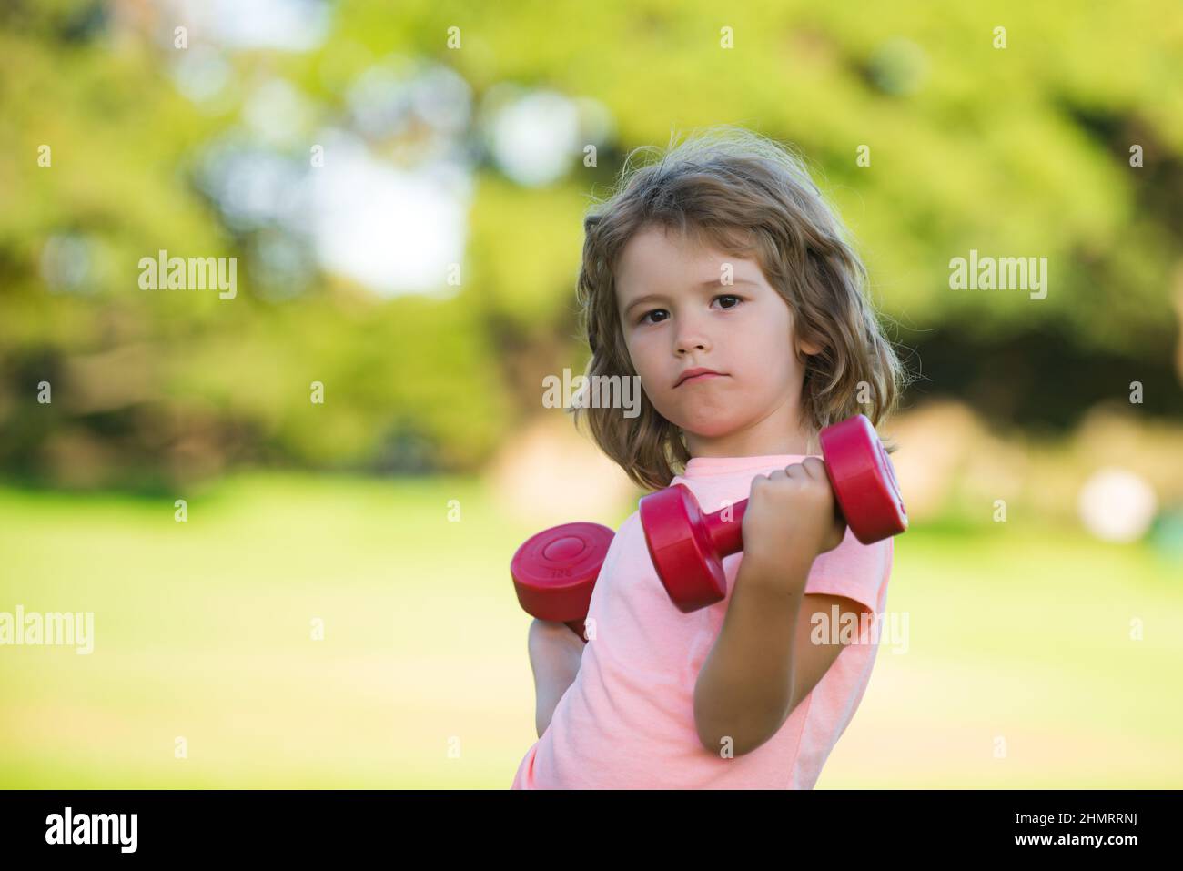 Sport child boy with strong biceps muscles. Kids exercising fitness dumbbells. Strong little boy ...