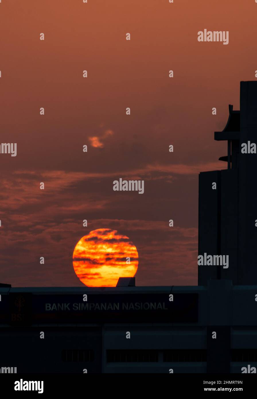 tropical sunset setting down behind building Stock Photo - Alamy