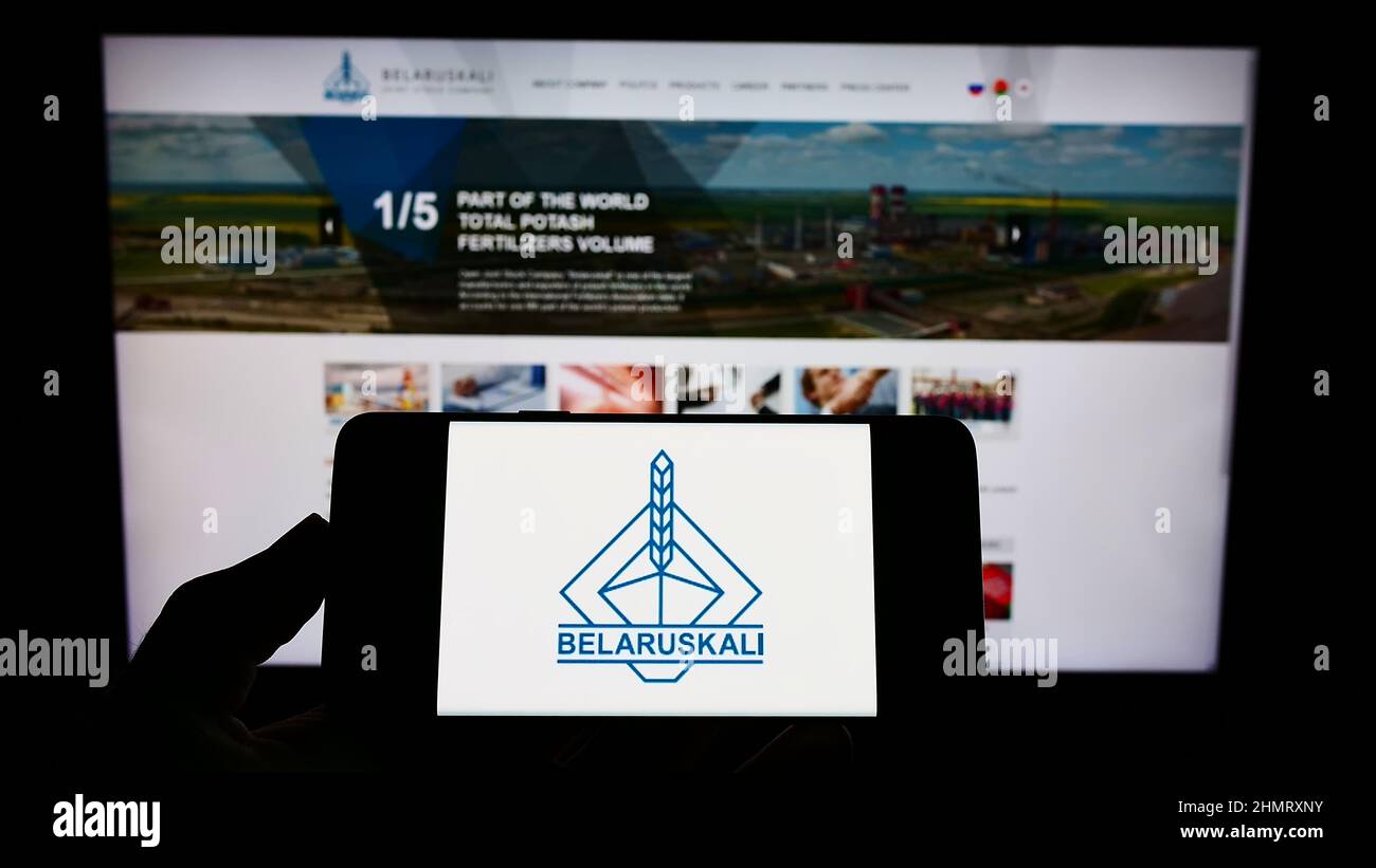 Person holding mobile phone with logo of Belarusian potash company ...