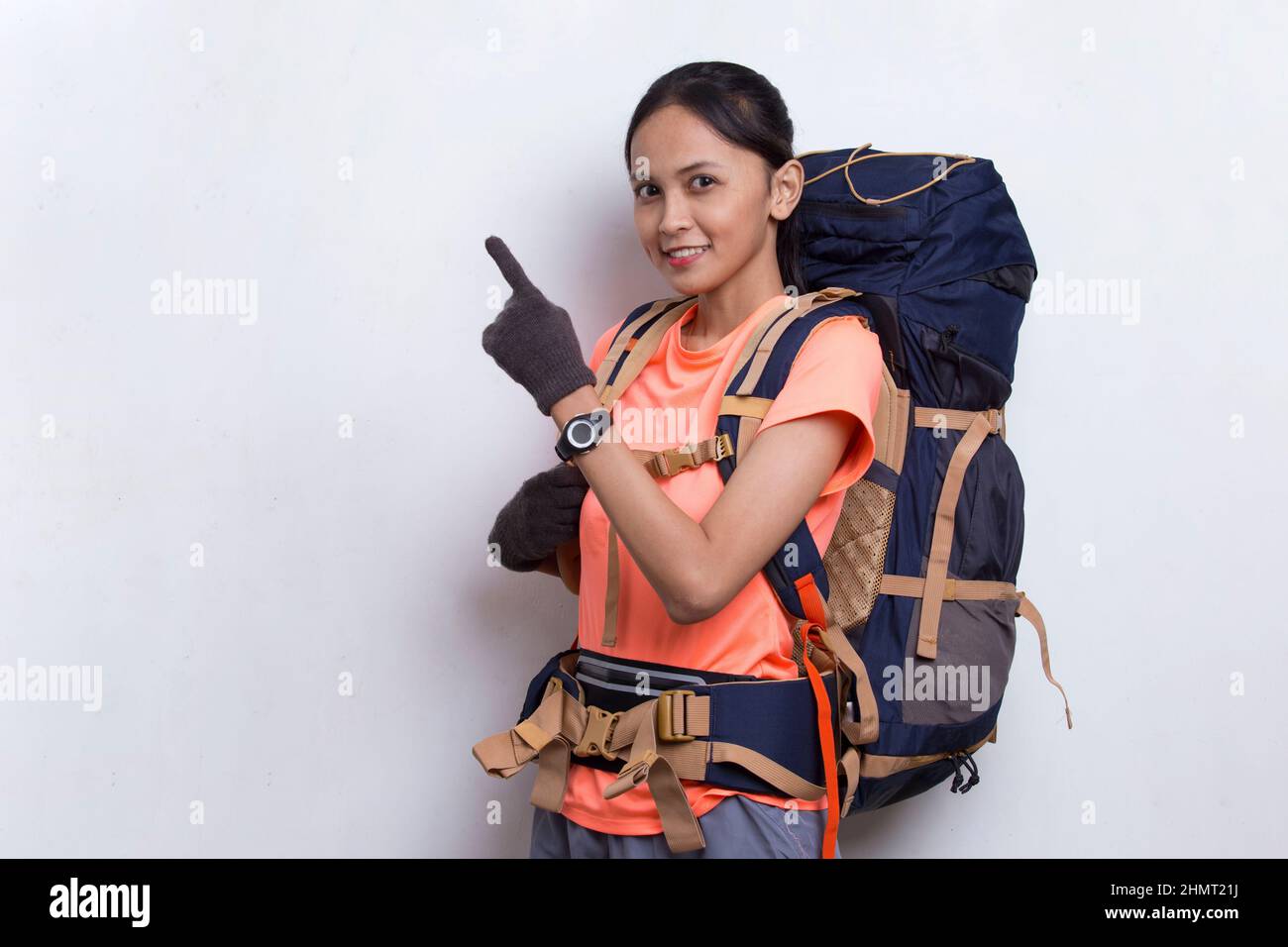 Young asian hiker woman with backpack pointing finger on empty space on ...