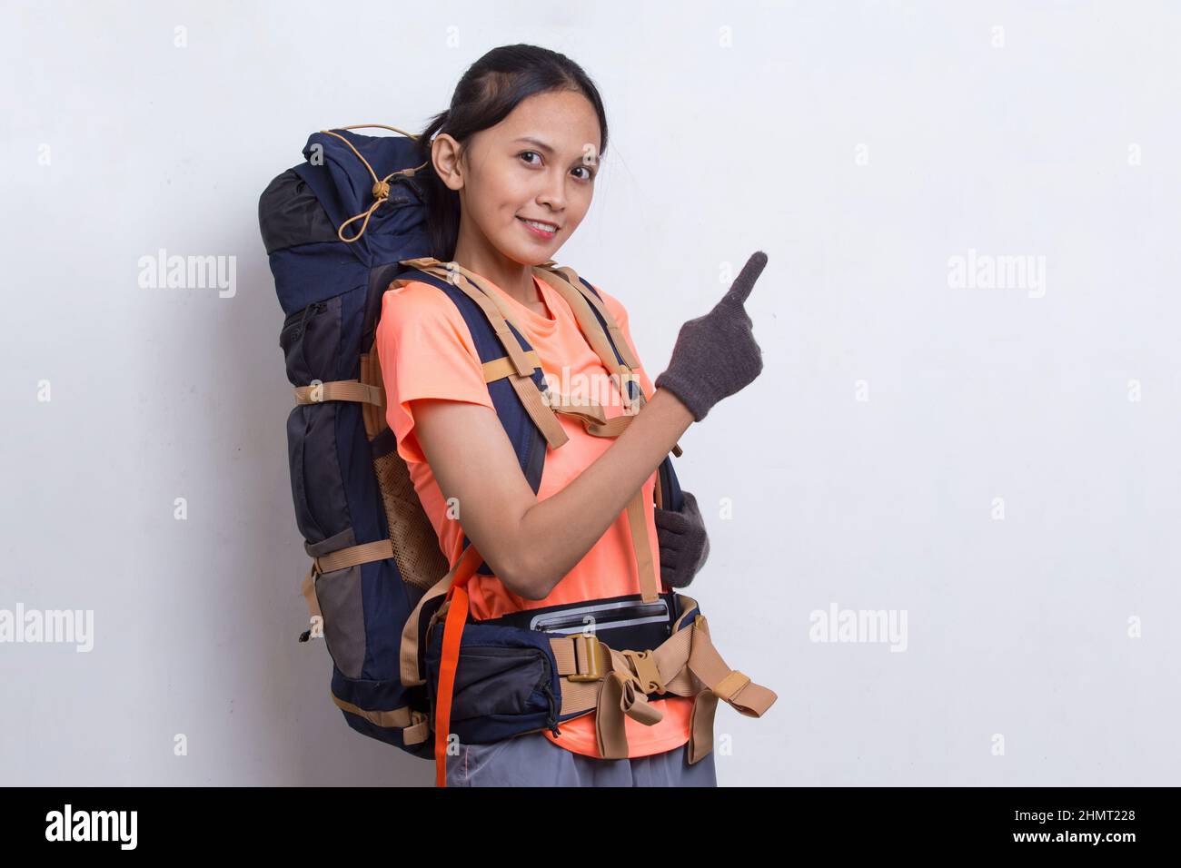 Young asian hiker woman with backpack pointing finger on empty space on ...