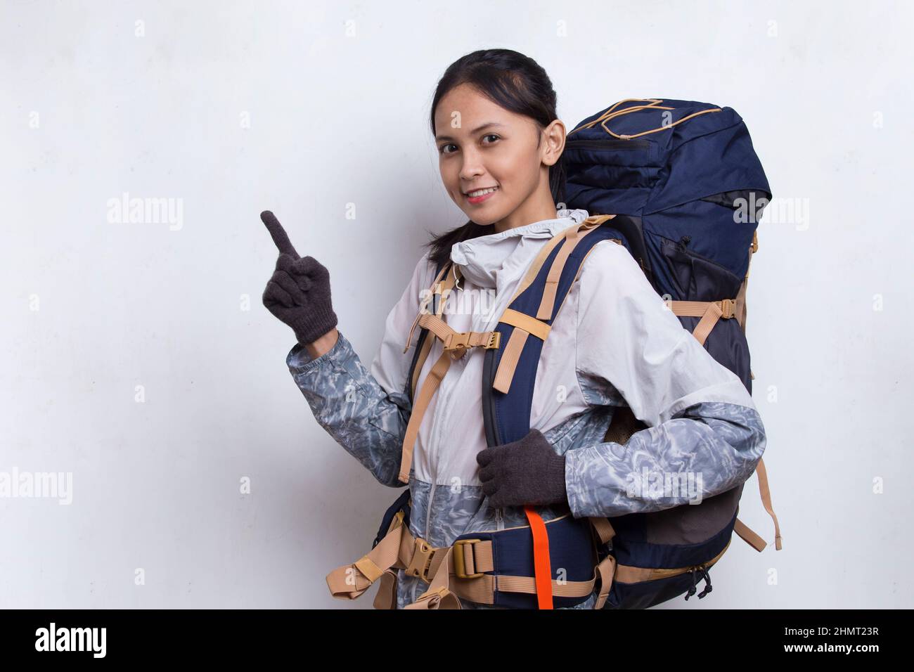 Young asian hiker woman with backpack pointing finger on empty space on ...