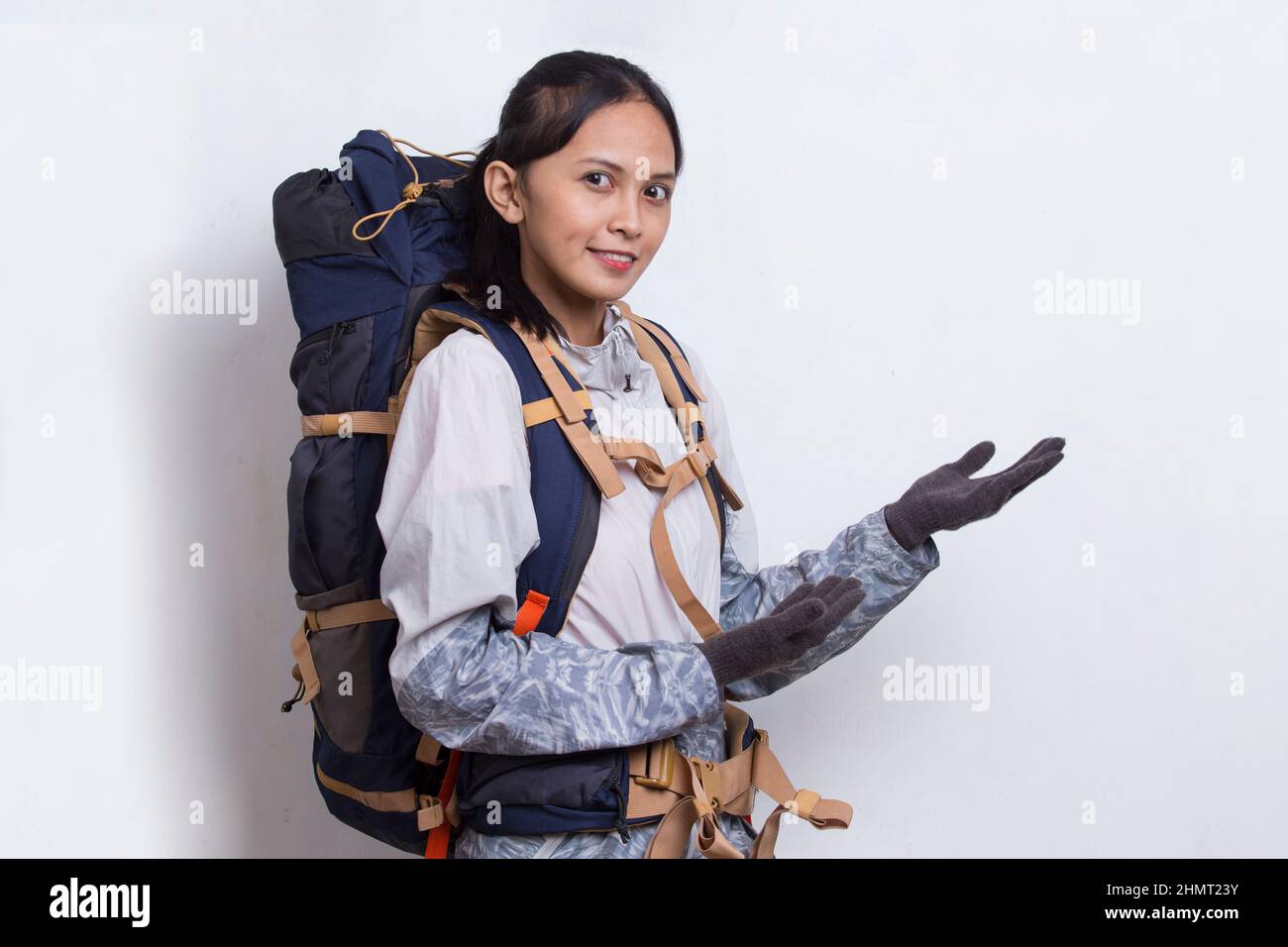 Young asian hiker woman with backpack pointing finger on empty space on ...