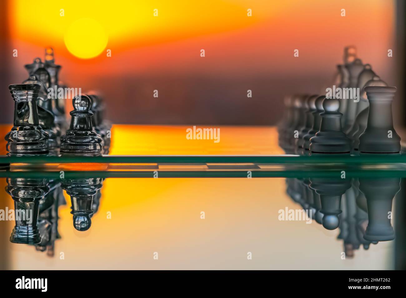 A glass chess set on a glass table seen from the side with a horizontal ...