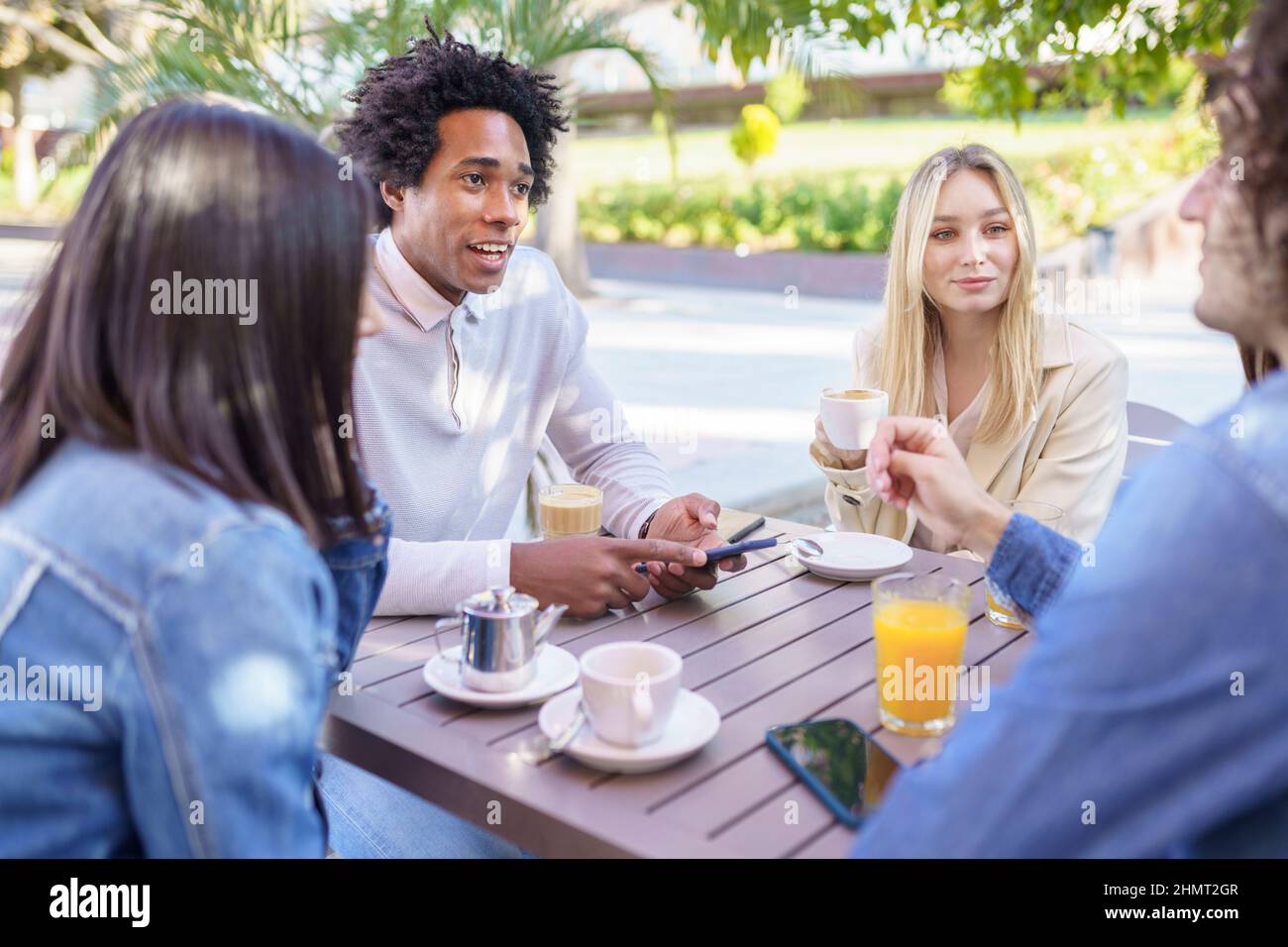 Multi-ethnic group of friends having a drink together in an outdoor bar ...