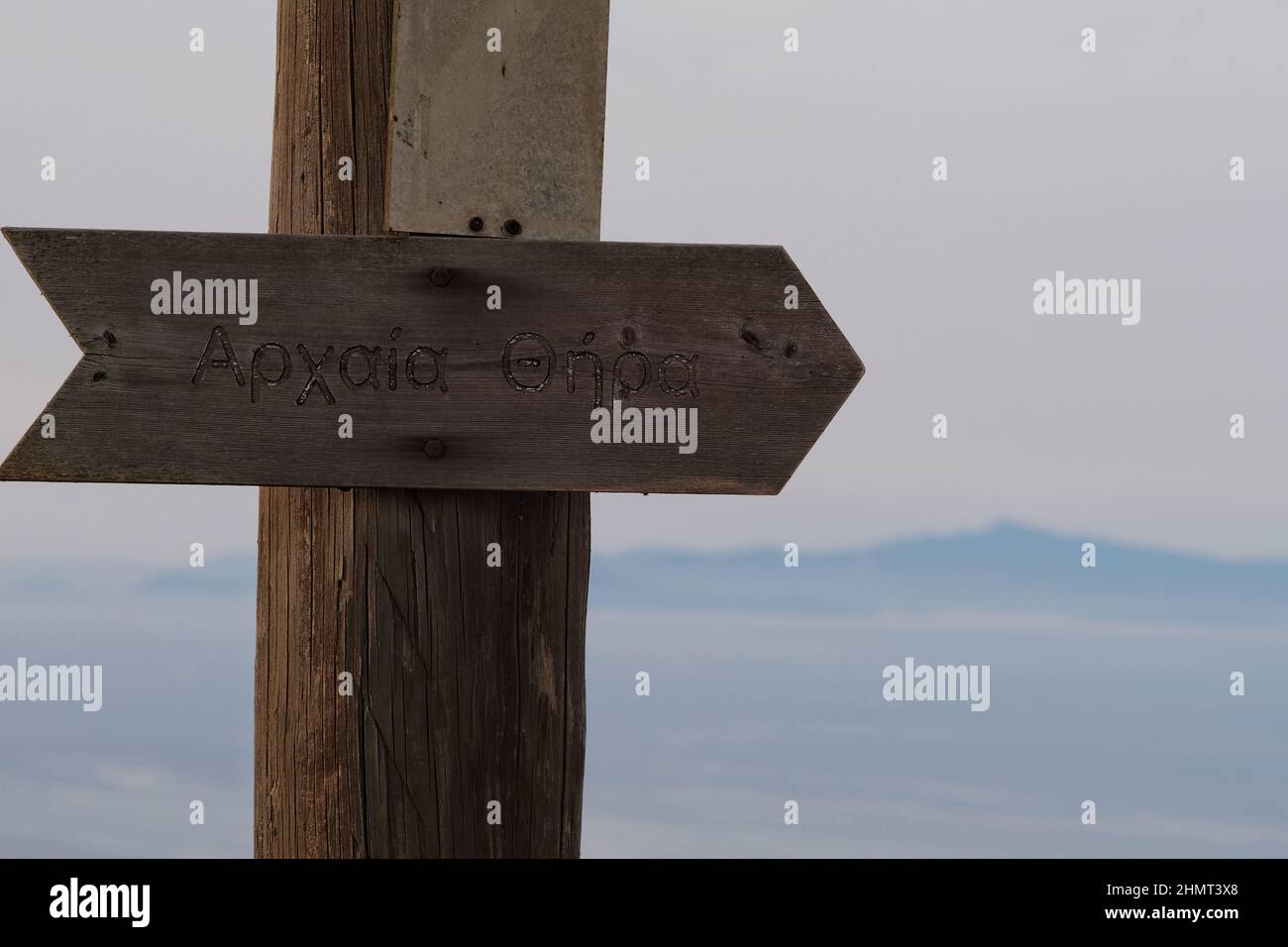 A wooden greek sign showing the path to the ancient village of Fira in ...
