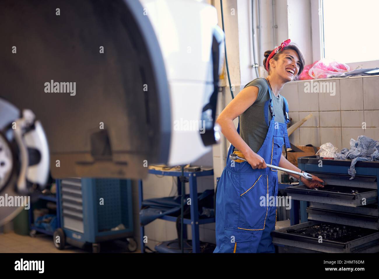A young cheerful female auto mechanic is working in a working ...
