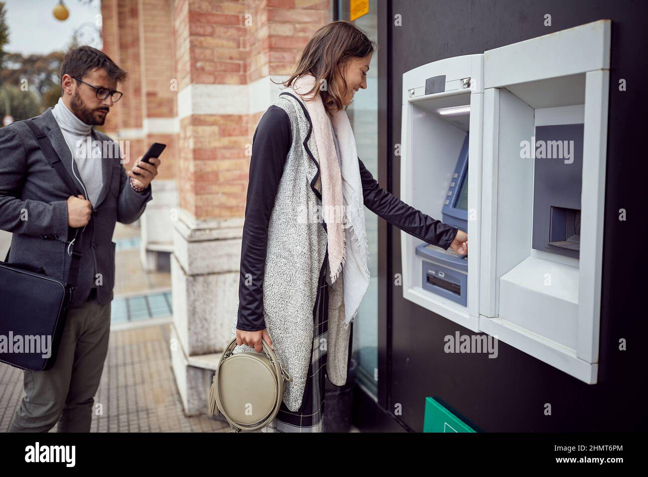 People in the row for ATM machine on the street on a cloudy day. Walk ...