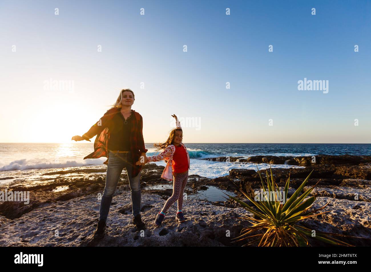 mother and daughter are walking near the ocean on the island of ...