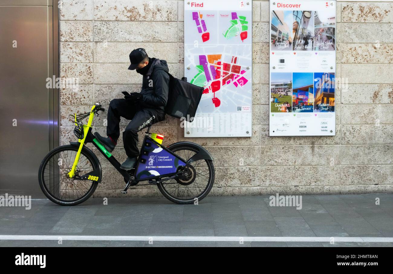Food delivery man checking maps and his phone for a destination in ...