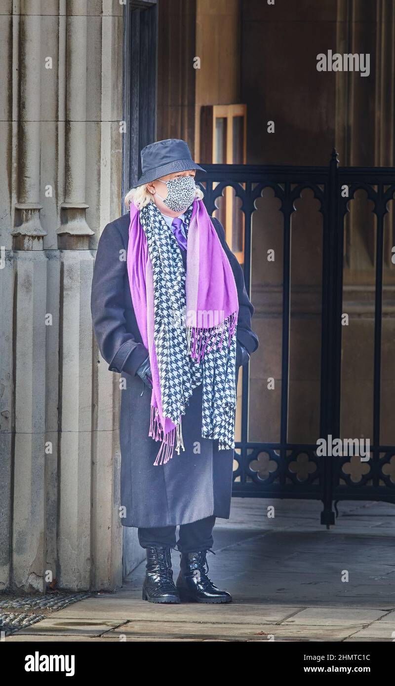 A female security guard, with face mask, on duty at the main entrnace ...