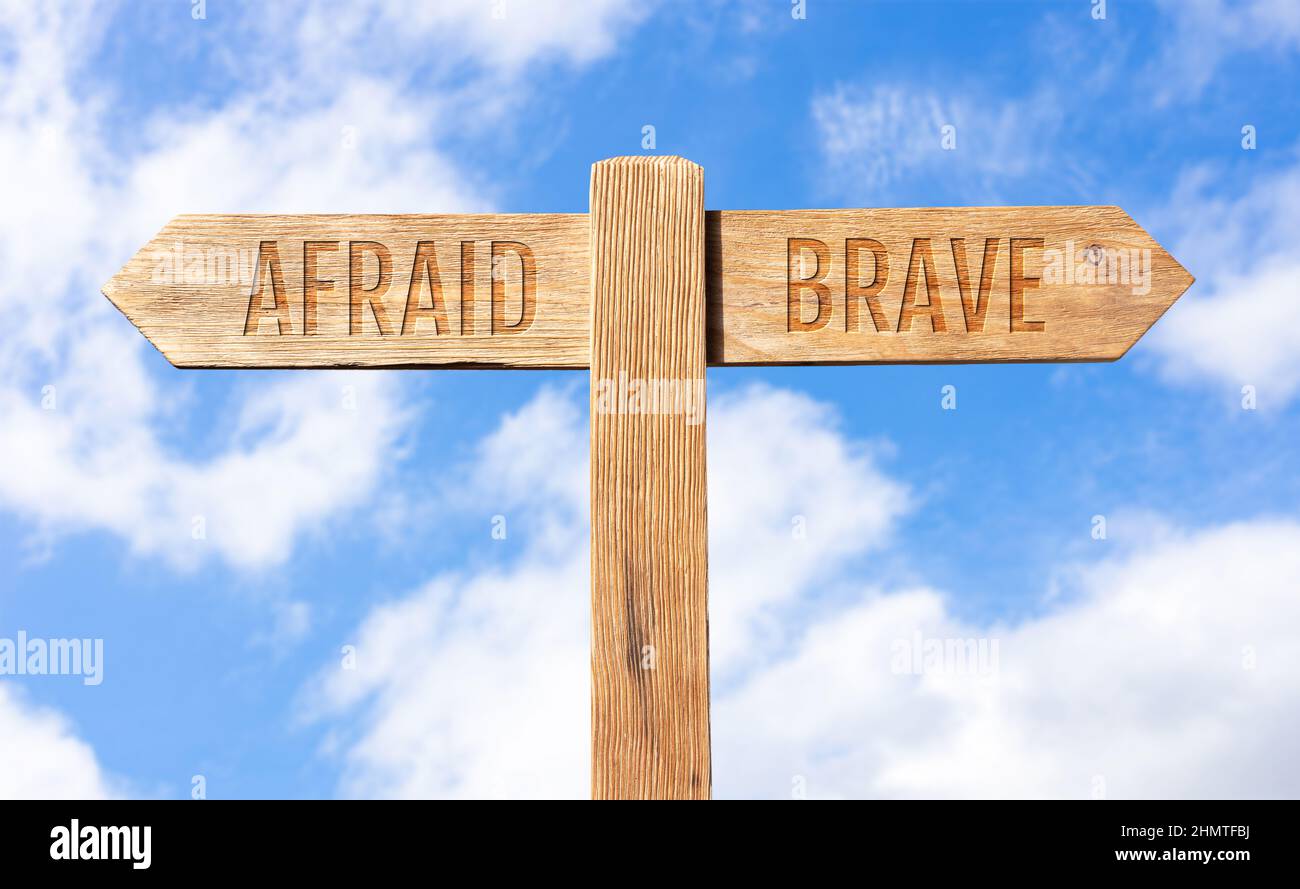 Afraid or brave concept. Wooden signpost with message on sky background ...