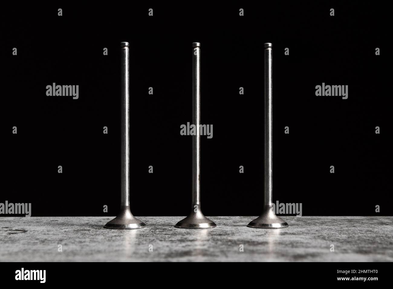 Three car engine valves on black background. Part of an internal ...