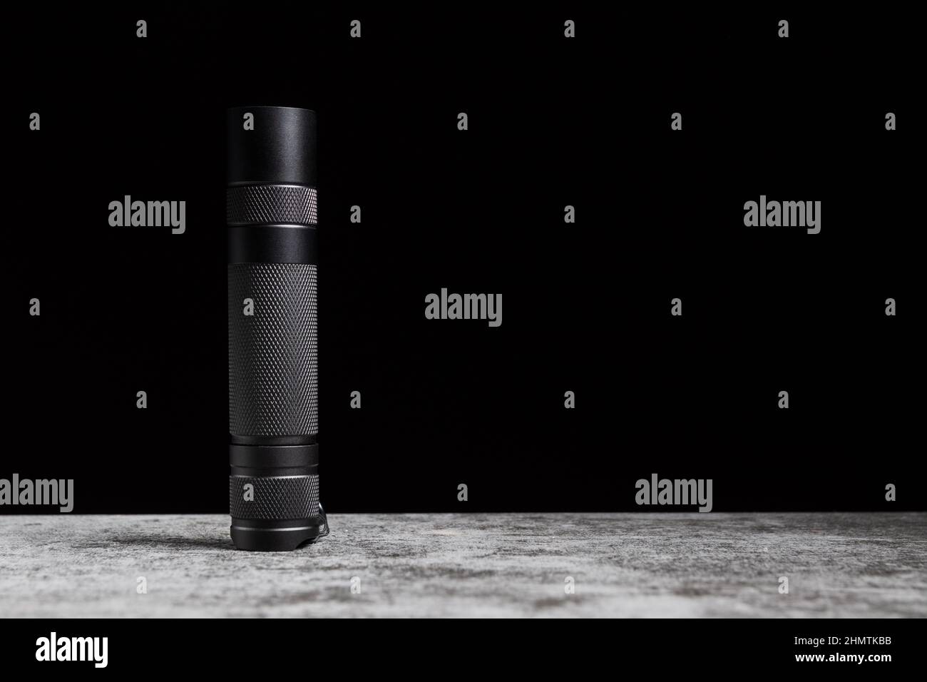 Flashlight stands on a table on a black background with copy space ...