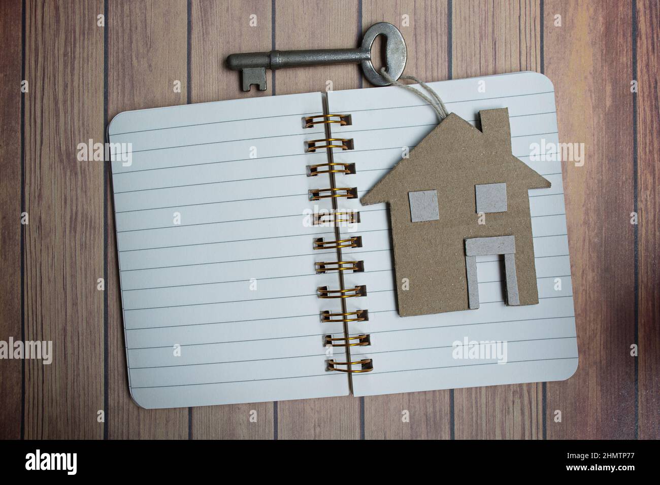 Notepad with house model and key on wooden desk. Directly above. Flat ...