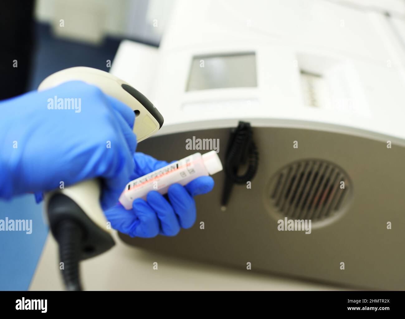 medical technician with blue rubber gloves scans the test tube code in ...