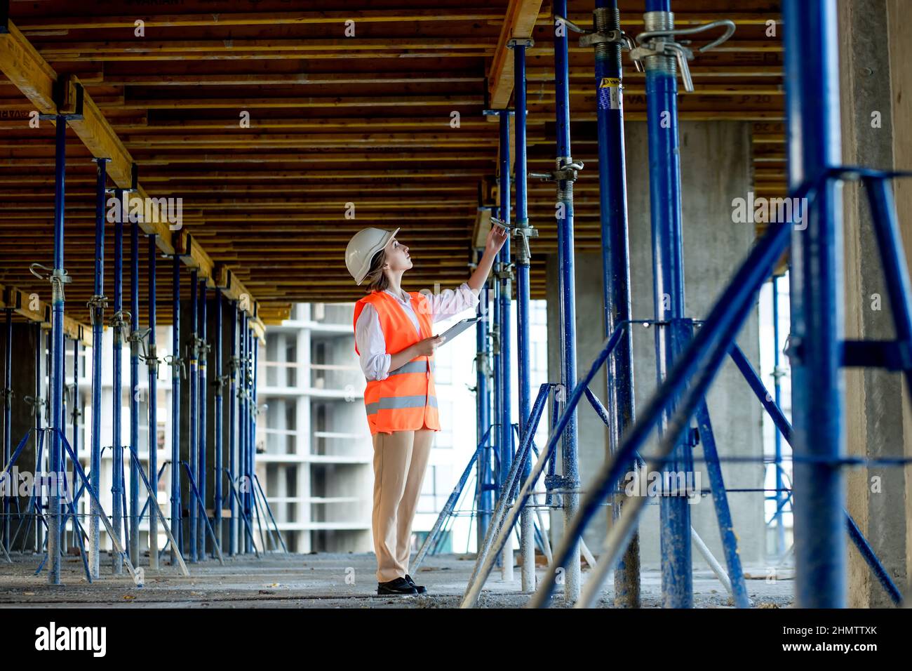 Confident Female builder checks fastenings on a monolithic structure ...