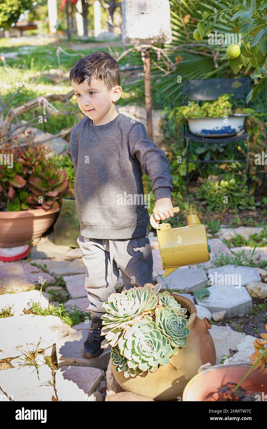 Little boy is watering plants on the backyard at home. Active preschool ...
