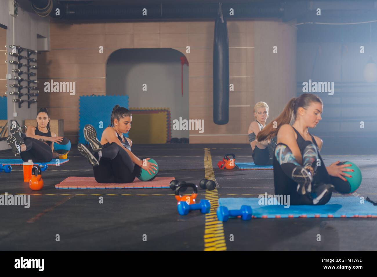Attractive sports girls practicing abs exercise with med ball in a ...