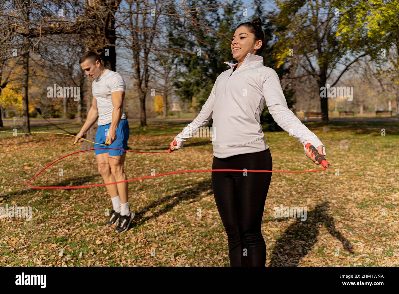 Two attractive and beautiful fit friends are jumping on the rope and ...