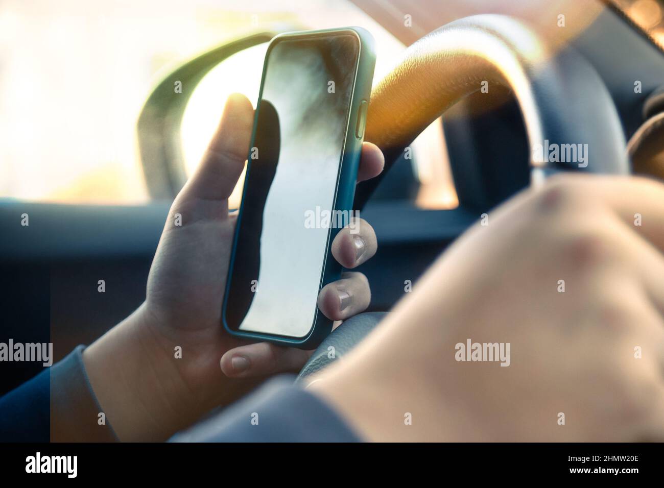 Teen drive a car and use smartphone. Young man reading messages holding ...