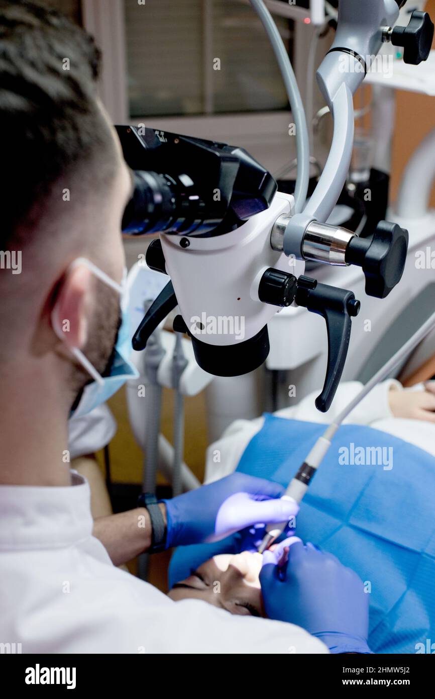 Dentist looking through a microscope at the patient's teeth. Modern ...