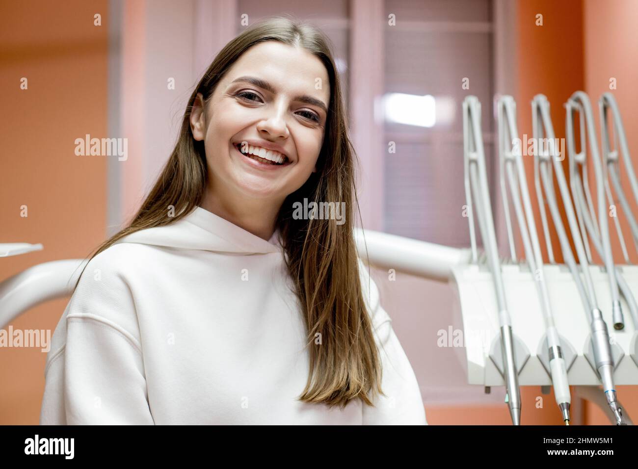 Happy smiling young woman with snow-white smile at dentist reception ...