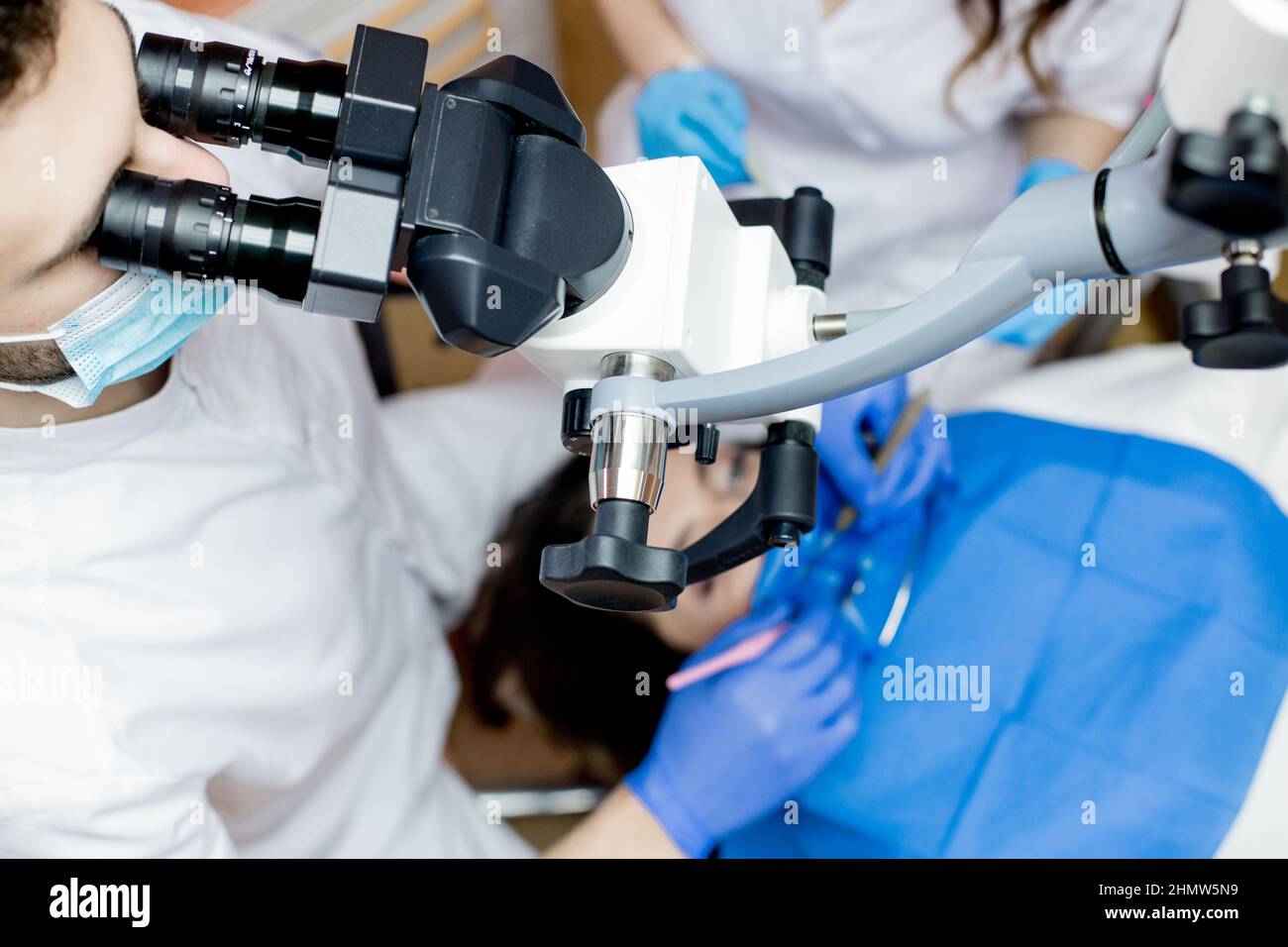 Dentist looking through a microscope at the patient's teeth. Modern ...